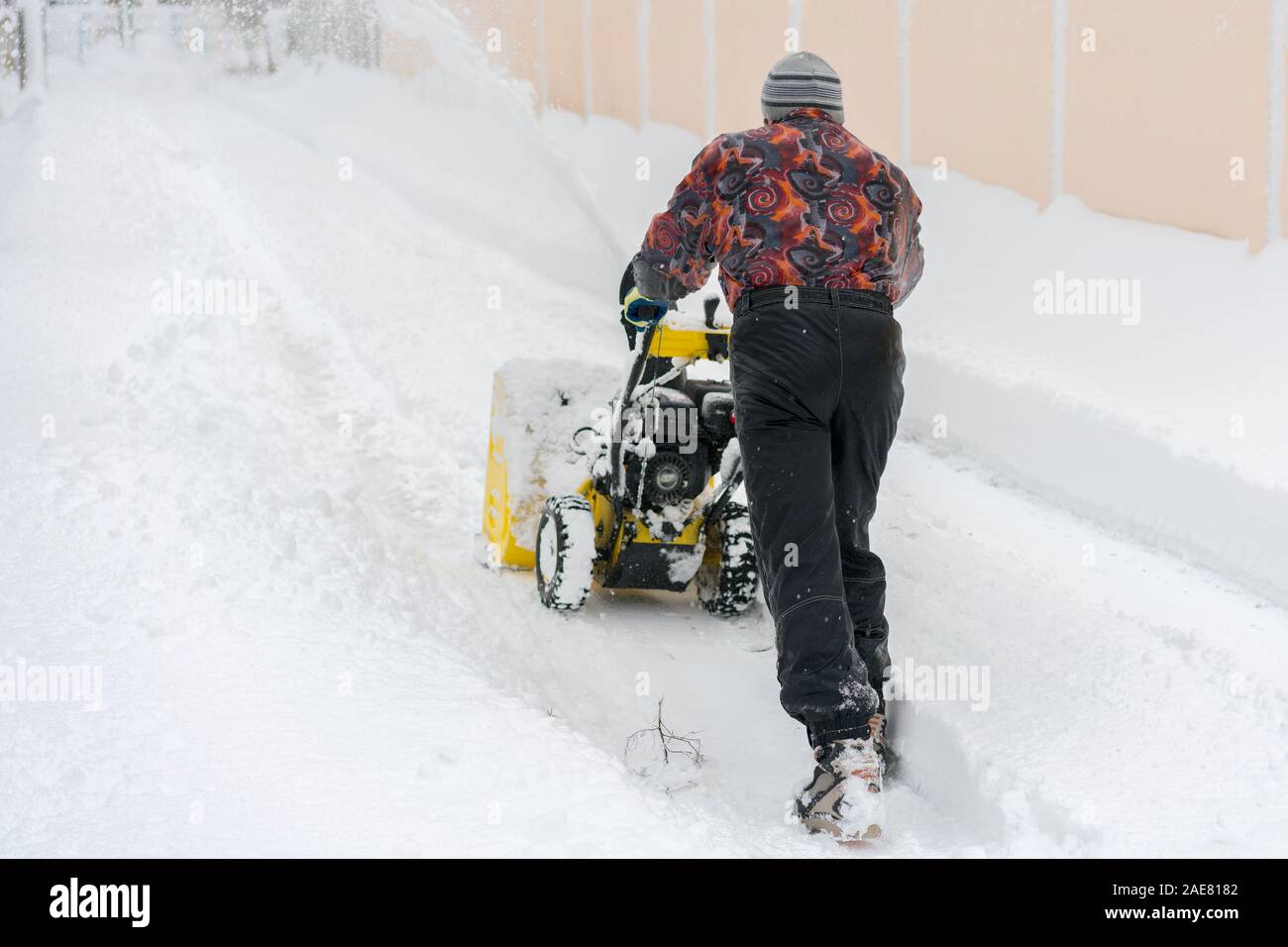 man operating snow blower to remove snow on driveway. Man using a ...