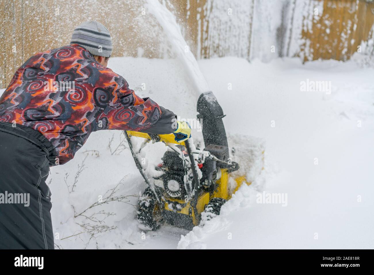 man operating snow blower to remove snow on driveway. Man using a ...