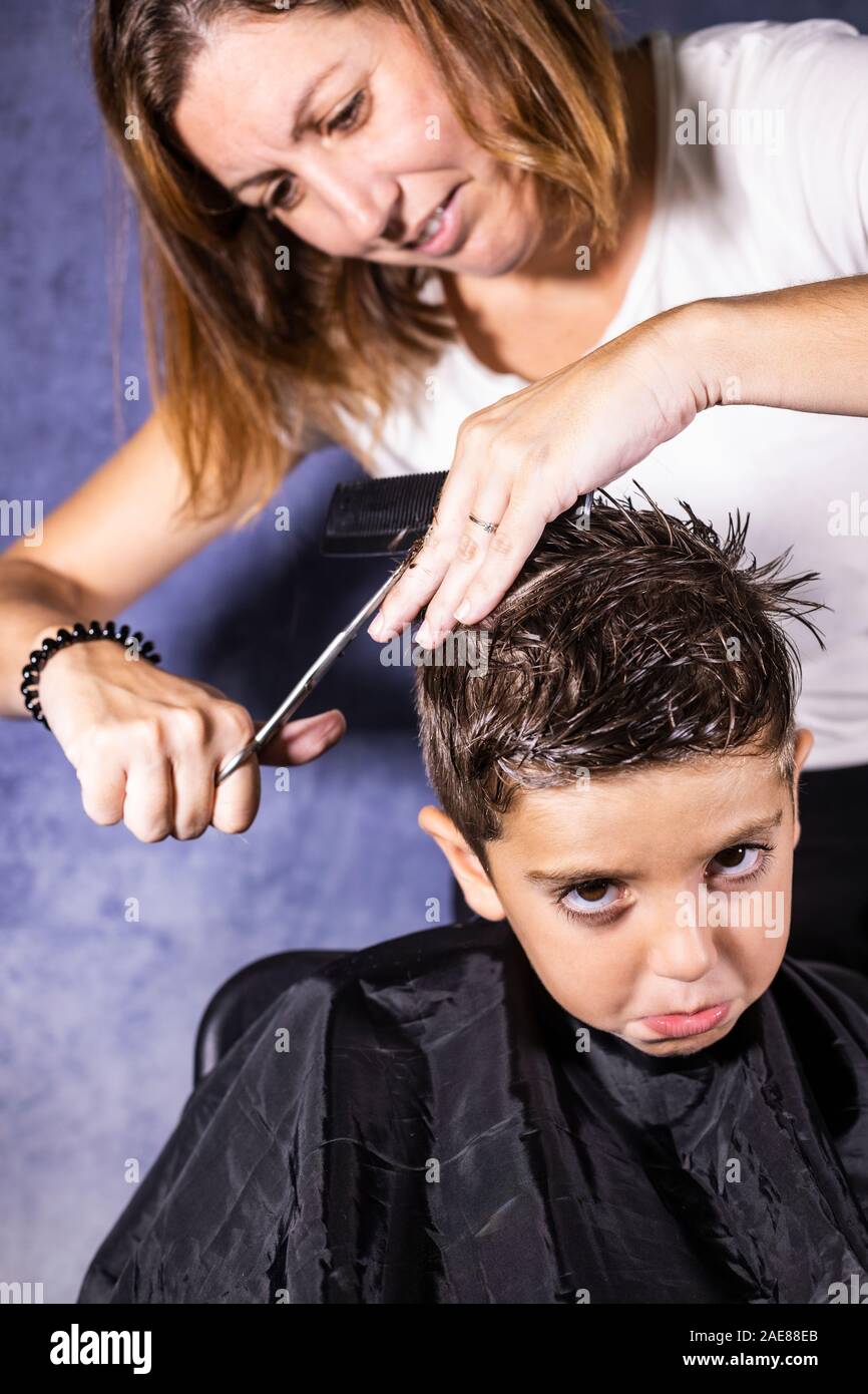Beautiful boy getting a haircut with scissors Stock Photo - Alamy