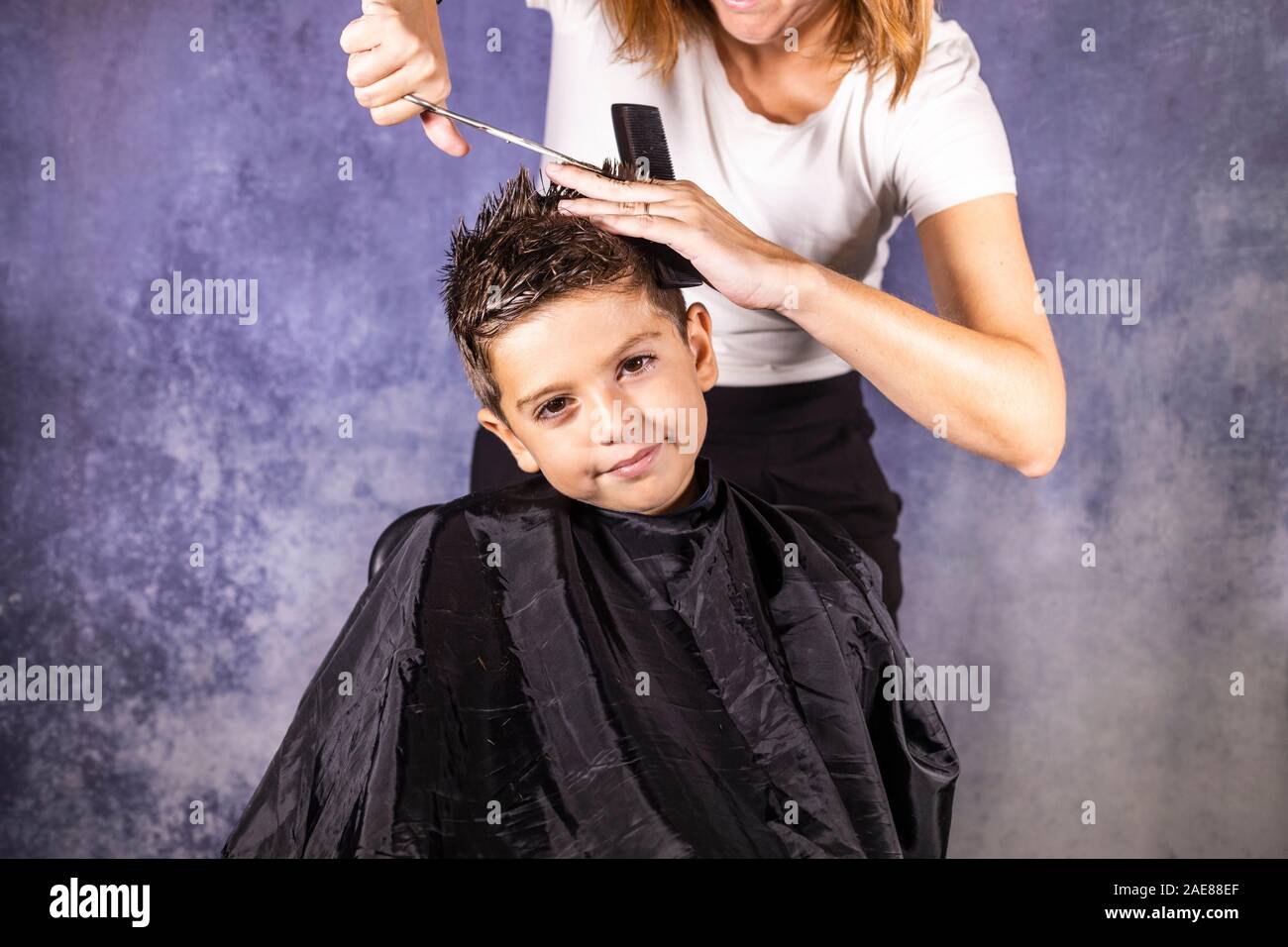 Beautiful boy getting a haircut with scissors Stock Photo - Alamy
