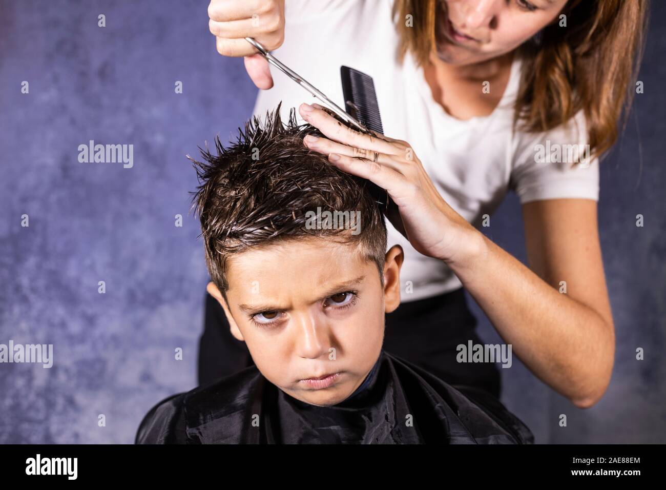 Beautiful boy getting a haircut with scissors Stock Photo - Alamy