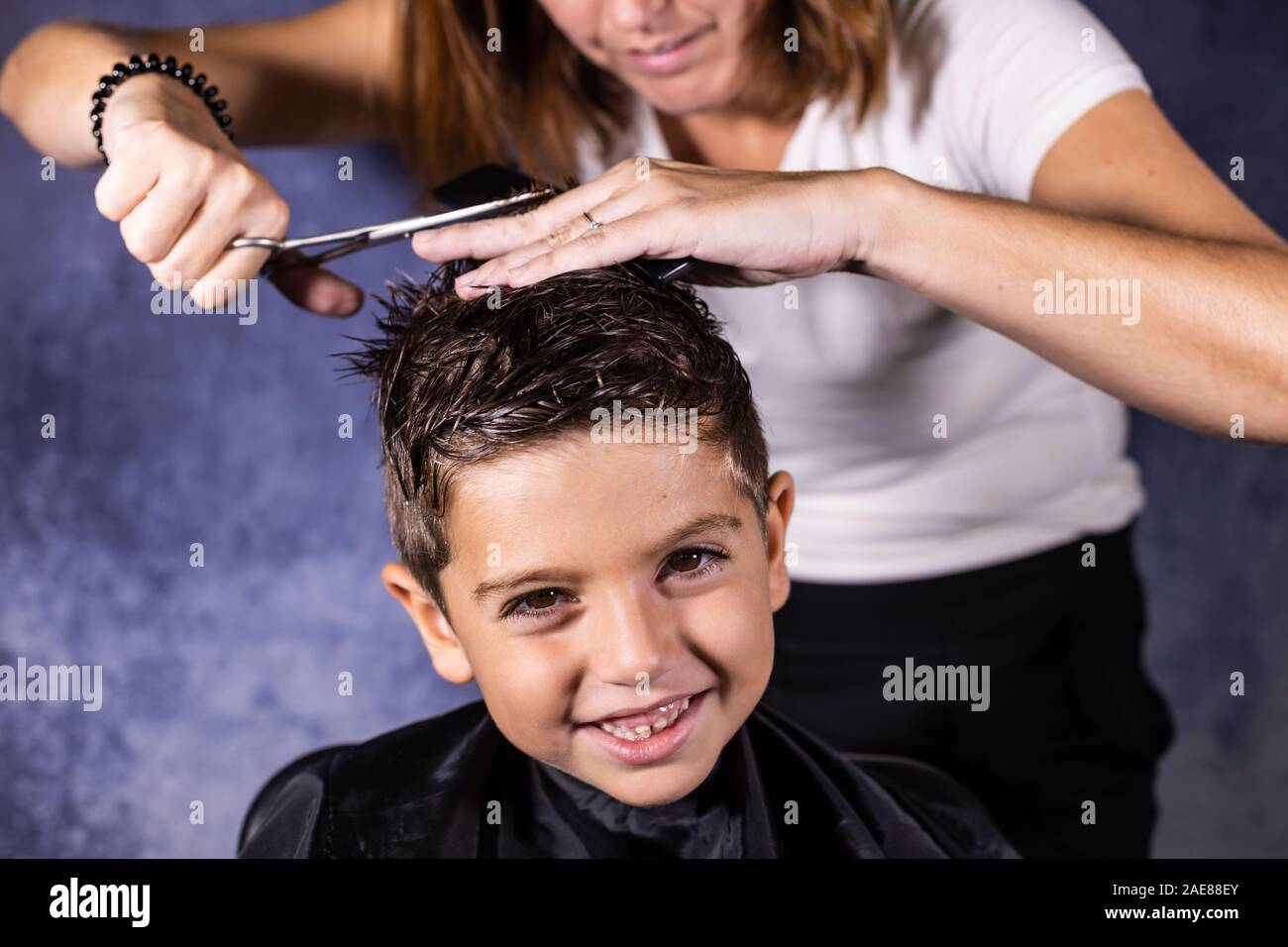 Beautiful boy getting a haircut with scissors Stock Photo - Alamy