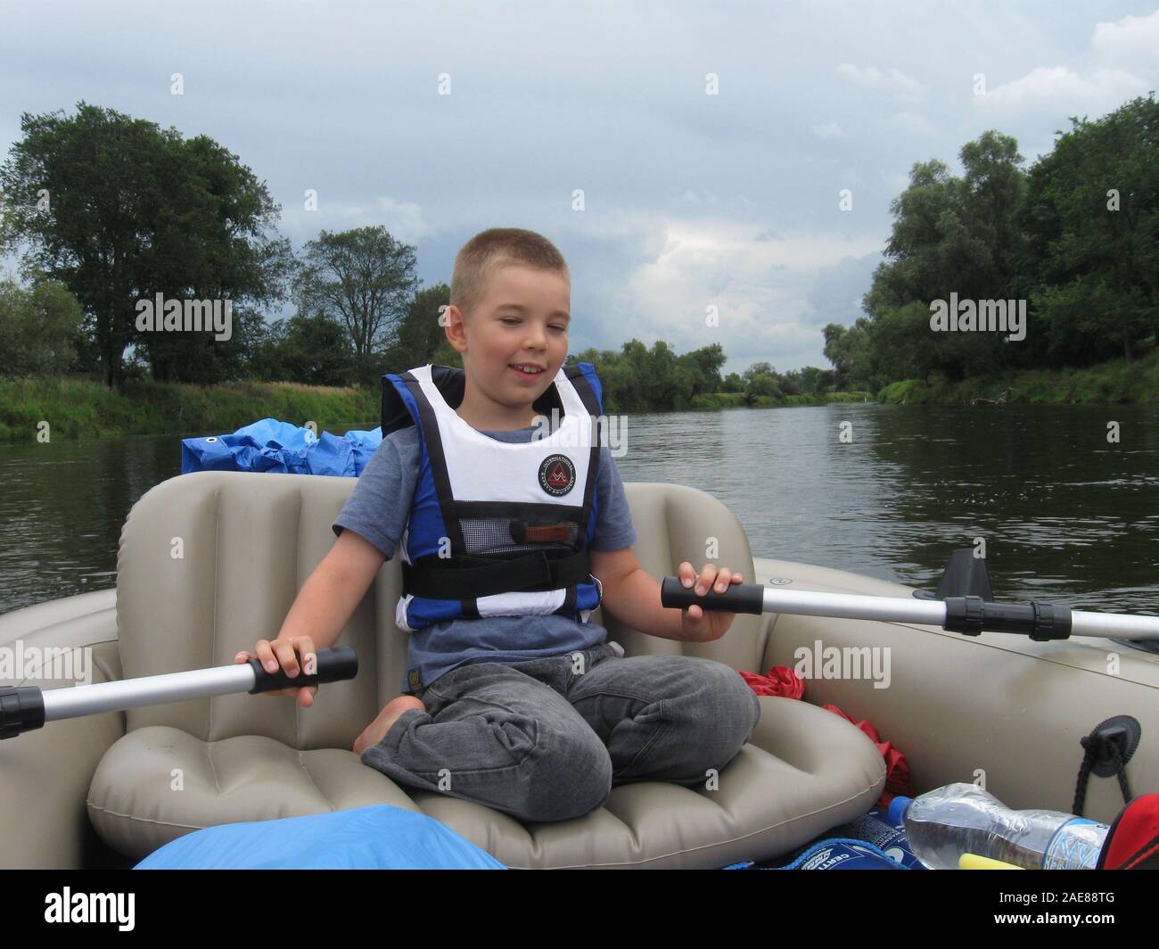 Boy rowing or resting on a rubber inflatable boat, during a vacation ...