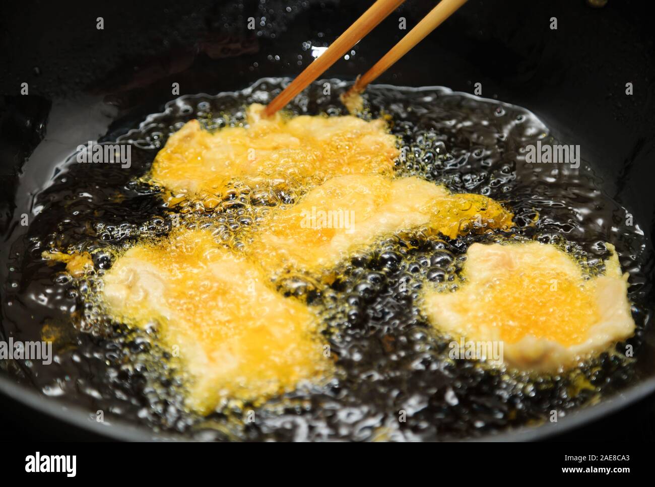 gold color meat in boiling oil on black background Stock Photo - Alamy