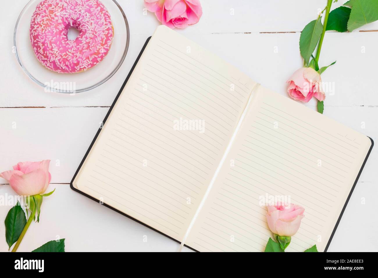 Open notebook with pastel pink roses and pink glazed donut Stock Photo ...