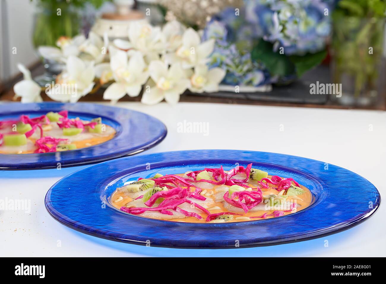 Front view of cod carpaccio with tomato cream, red cabbage, kiwi and ...