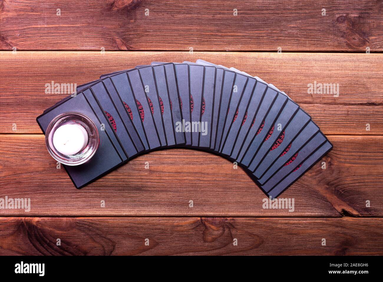 Fortune telling cards on a wooden table with a burning candle. Top view ...