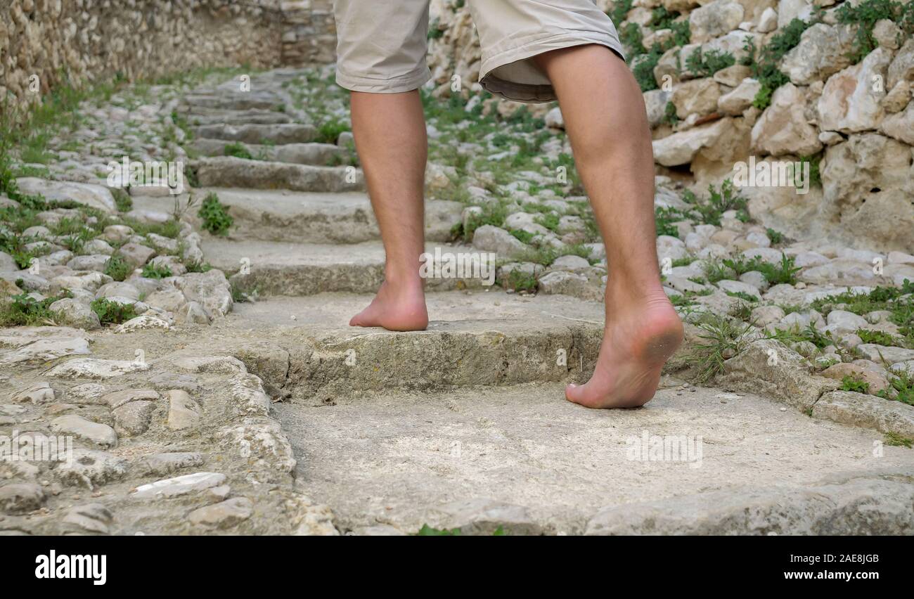Pilgrim goes to a significant place with bare feet on stone steps ...
