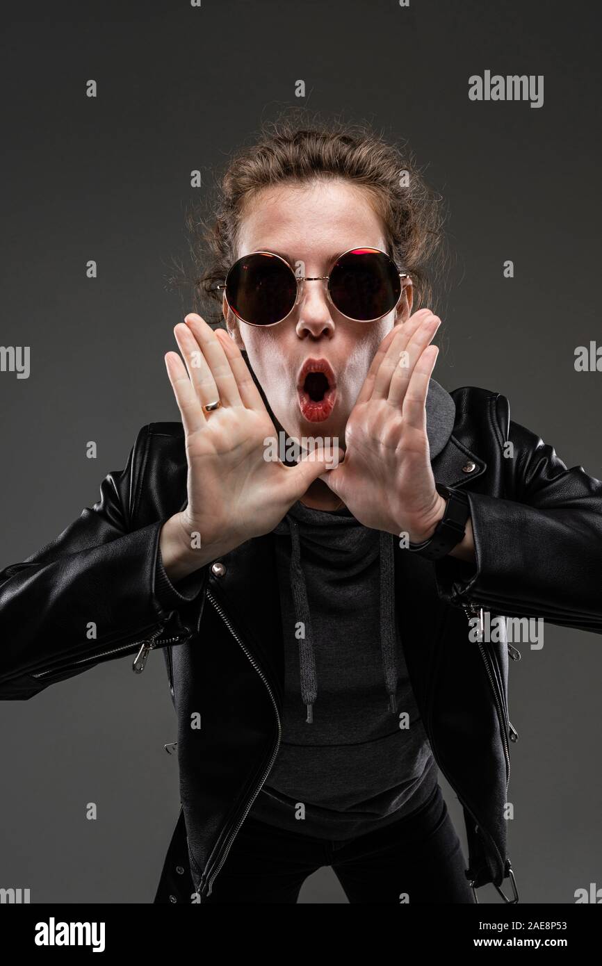 A young girl with rough facial features in a black jacket screams on ...