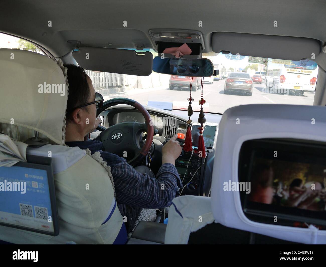A taxi driver in Beijing, China and screens for advertisement inside ...