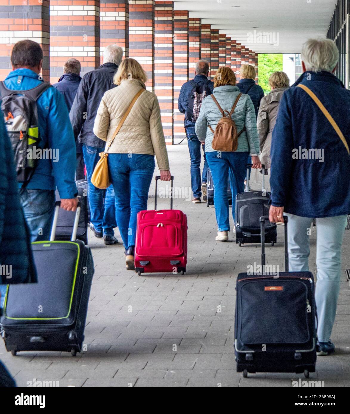 Group of tourists pulling luggage on wheels walking along pavement ...