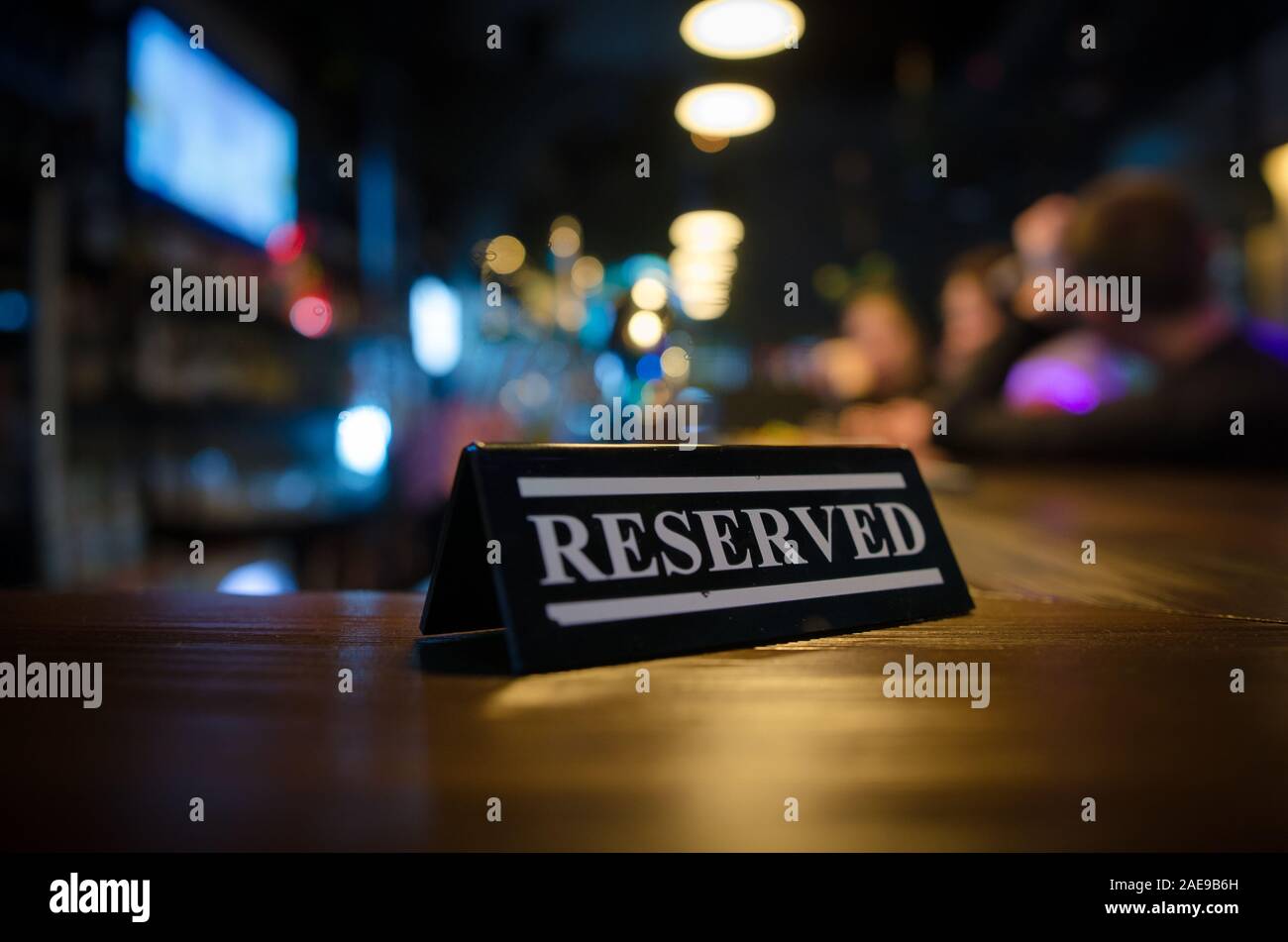 Reserved sign standing on wooden table in bar. Pub interior background ...