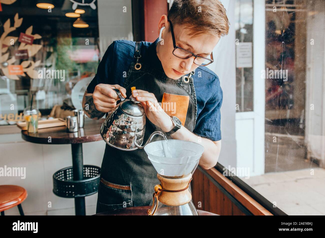 Barista preparing filter coffee outdoor. Young male barista pouring ...