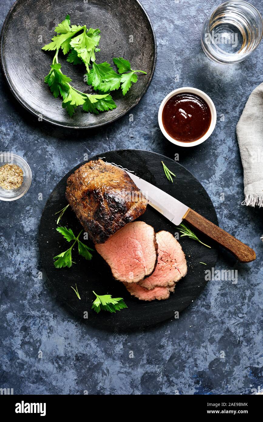 Sliced grilled beef on wooden board over stone background. Medium rare ...