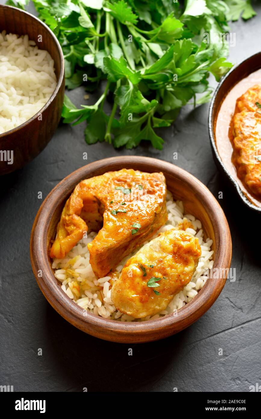 Fish curry with rice in wooden bowl on black stone table. Indian style ...