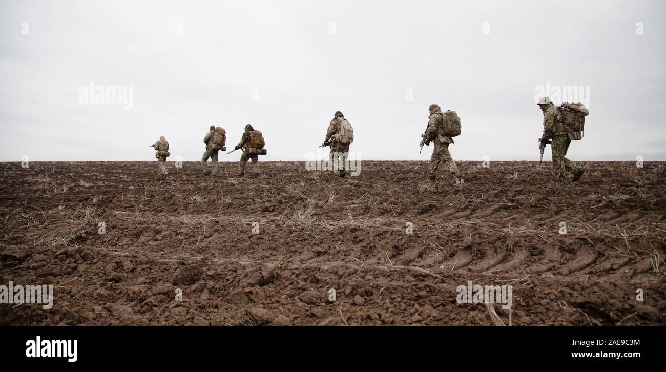 Army soldiers group on march in muddy field Stock Photo - Alamy