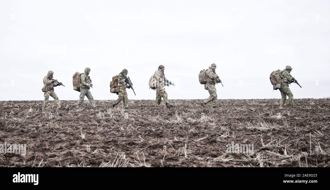 Army soldiers group on march in muddy field Stock Photo - Alamy