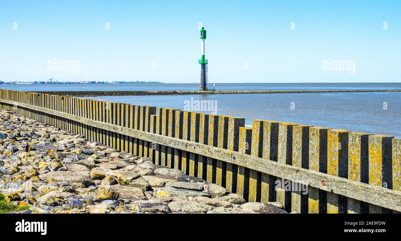 Seawall and green lateral buoy navigational marker on the Elbe River ...