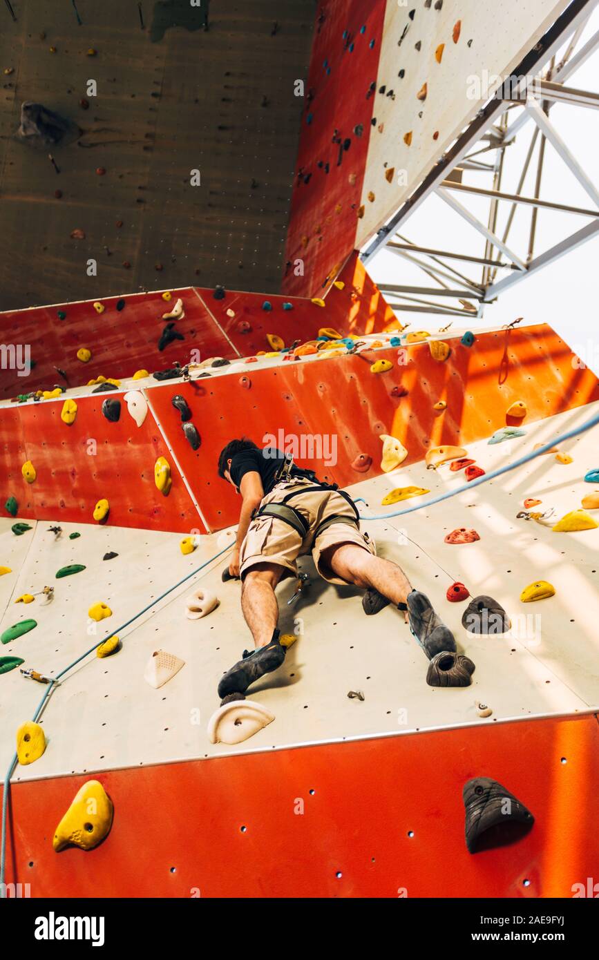 Young climber guy climbing on practical rock in climbing center ...
