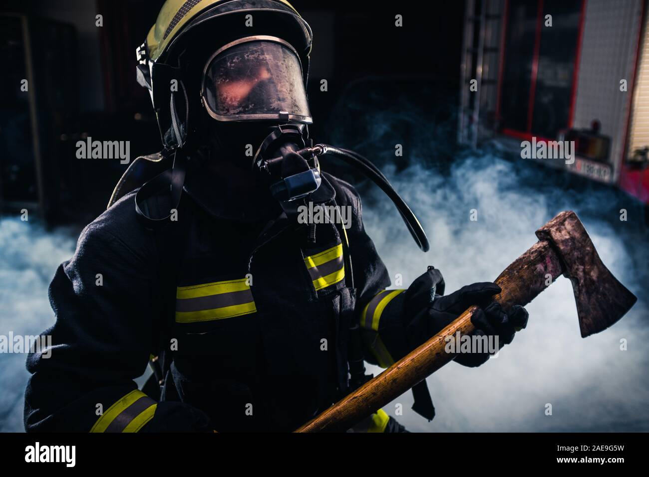 Portrait of a female firefighter while holding an axe and wearing an ...