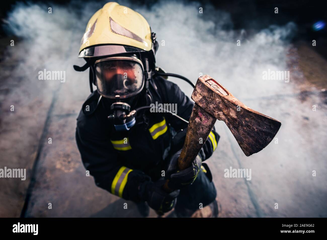 Portrait of a female firefighter while holding an axe and wearing an ...