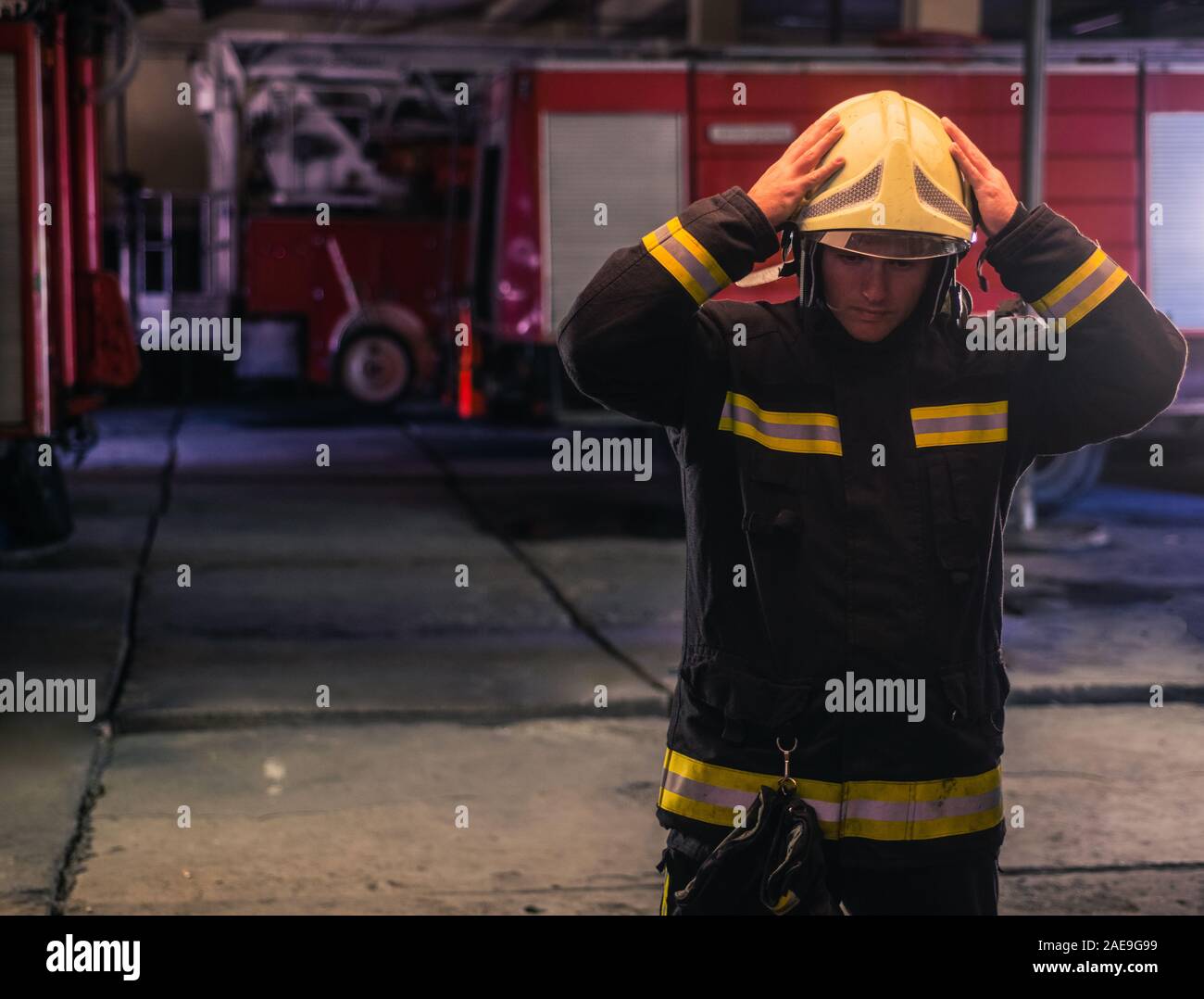 Portrait of young fireman standing inside the fire station Stock Photo ...