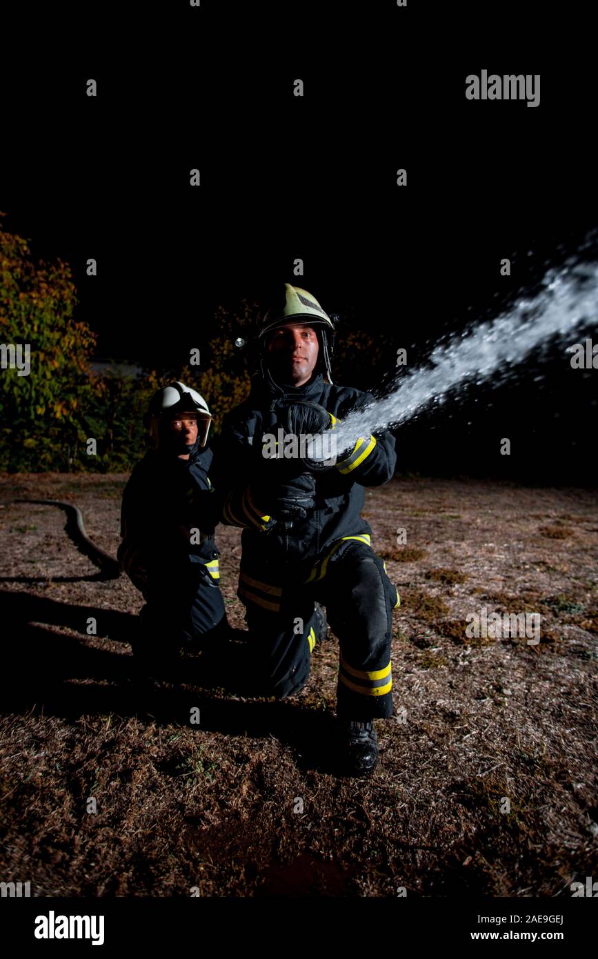Firemen using fire hose that shoots foam and water during an emergency ...