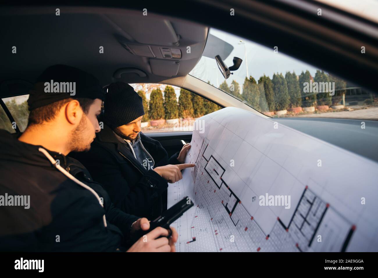 Two robbers planning and pointing on the blueprint(map) their objective ...
