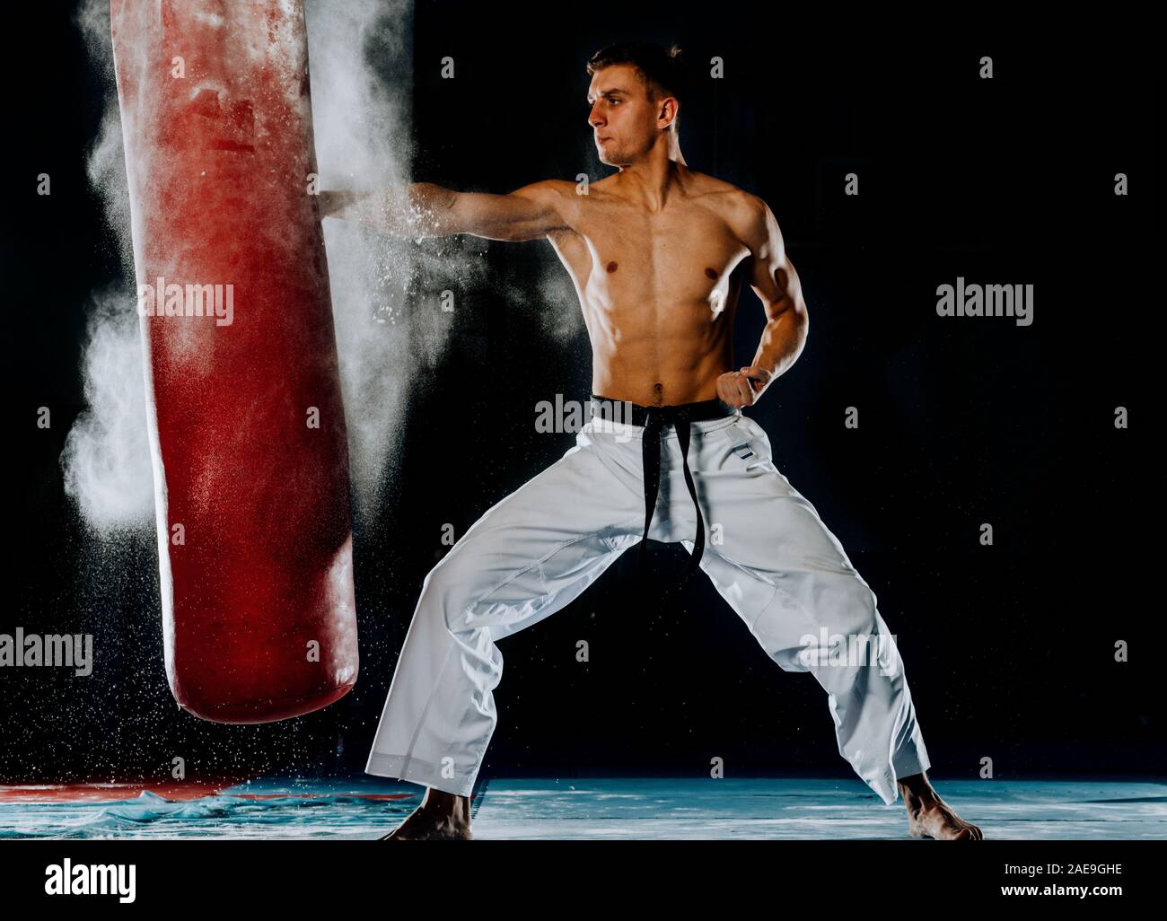 Portrait of a young athlete handsome sports man boxing red bag ...