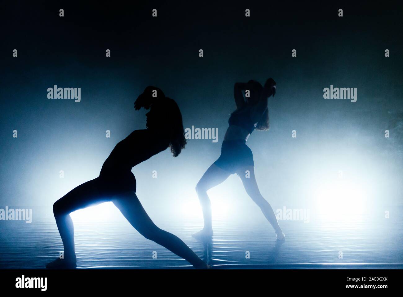 Pair of flexible silhouette girls performing an artistic dance movement ...