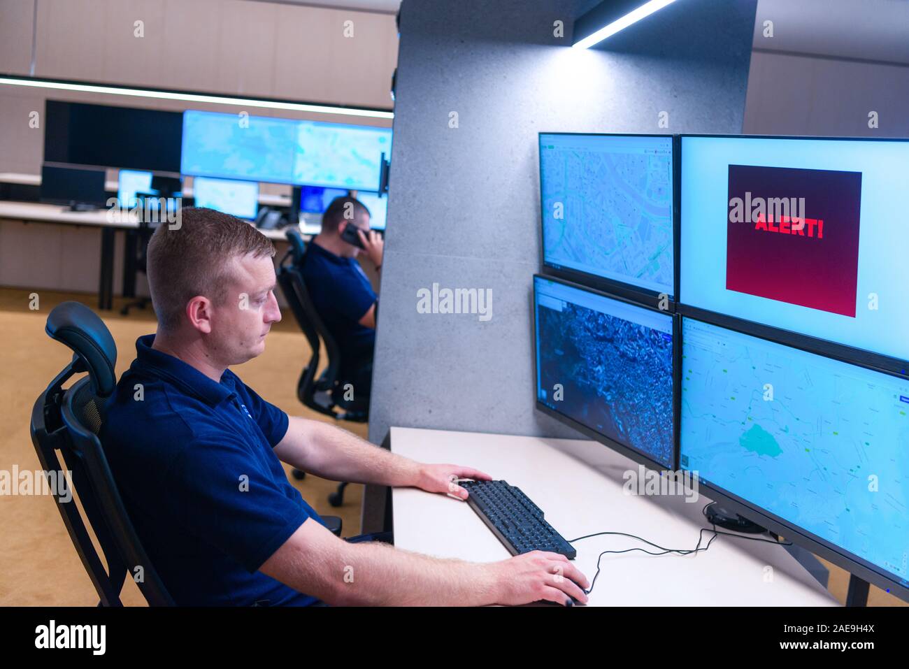In the Security Control Room Officer Monitors Multiple Screens while ...