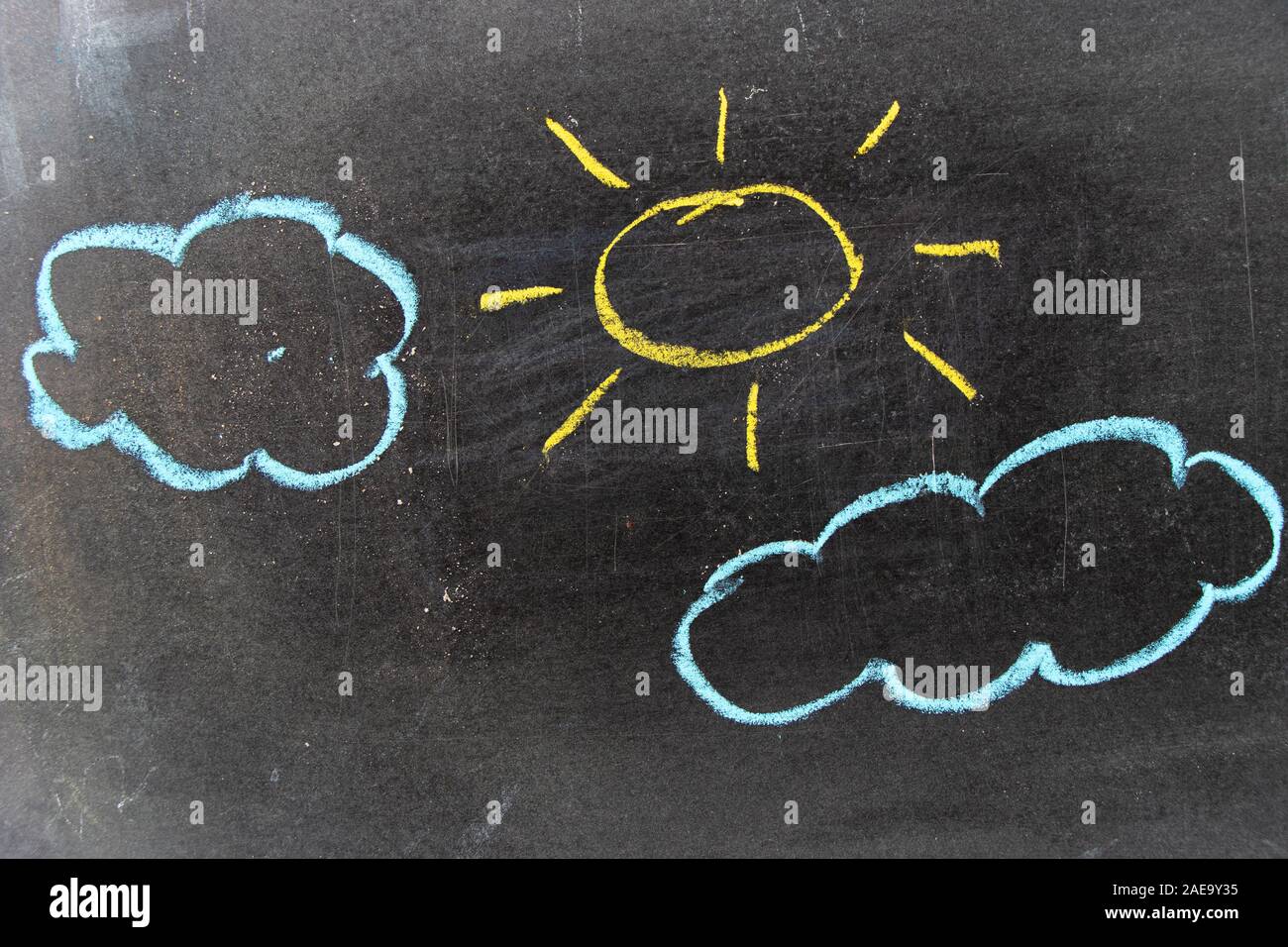 Color chalk hand drawing in yellow sun and blue cloud shape on ...