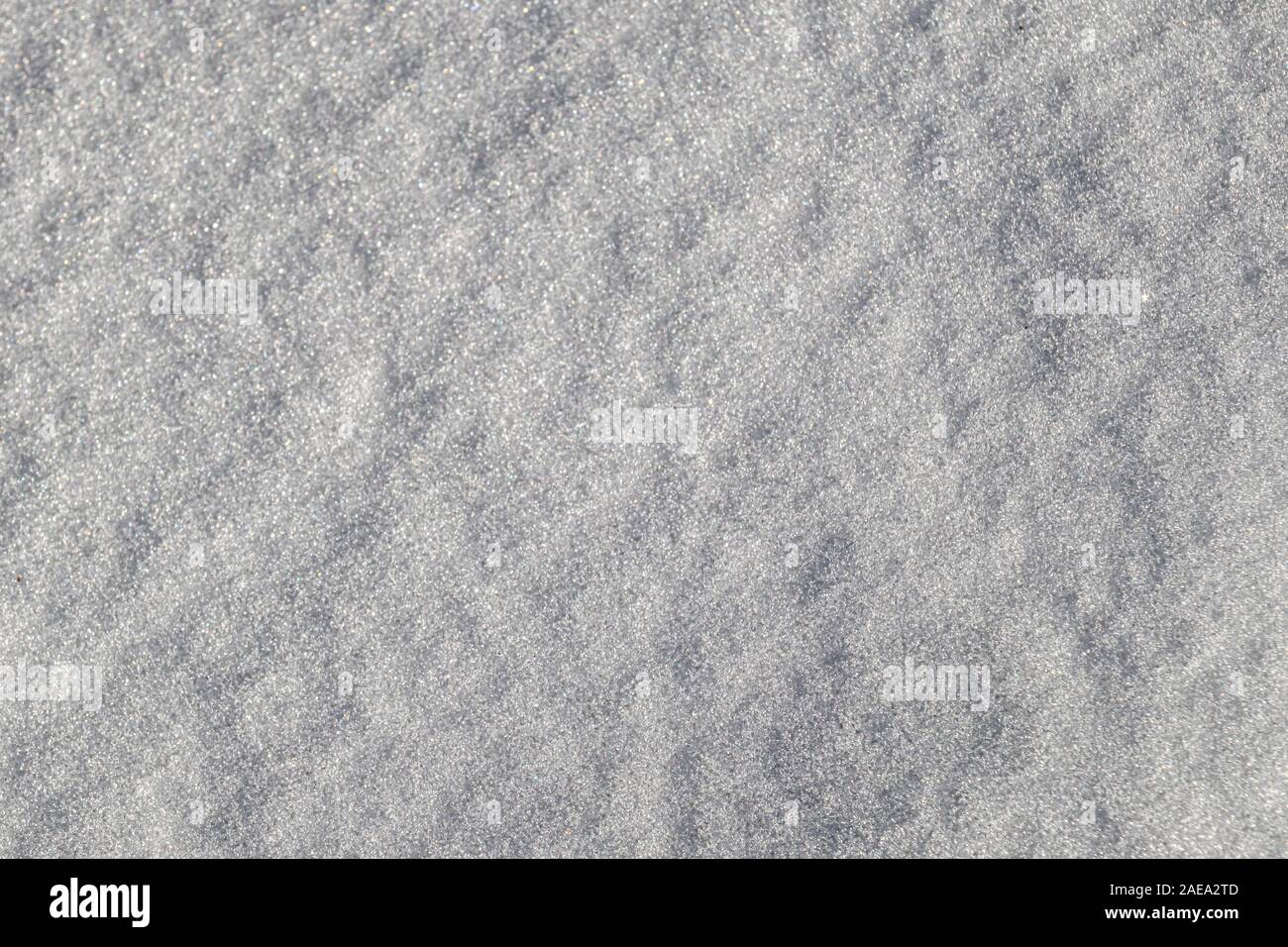 A close-up view of a surface covered in snow shows the grainy texture ...
