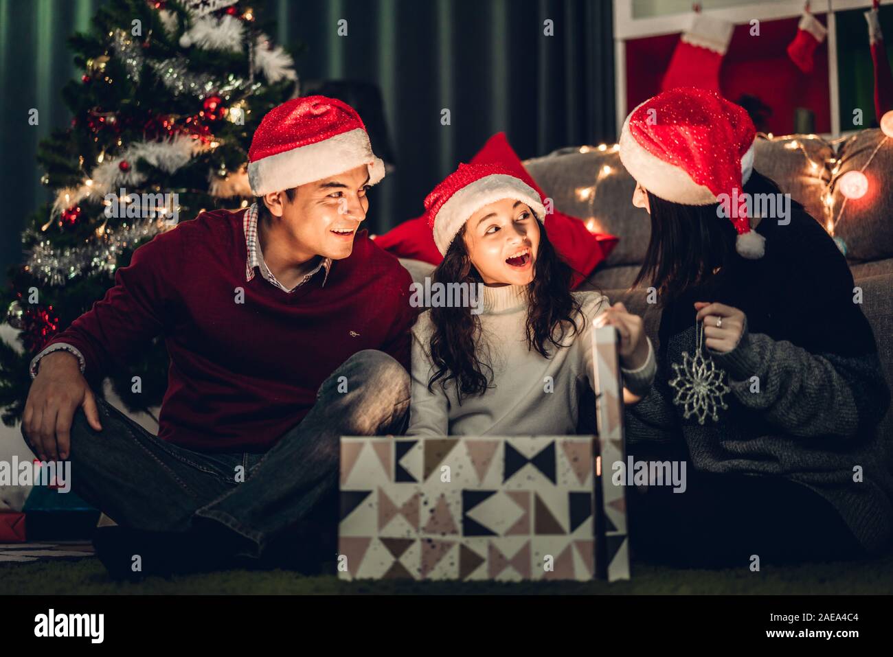 Portrait of happy family father and mother with daughter in santa hats ...
