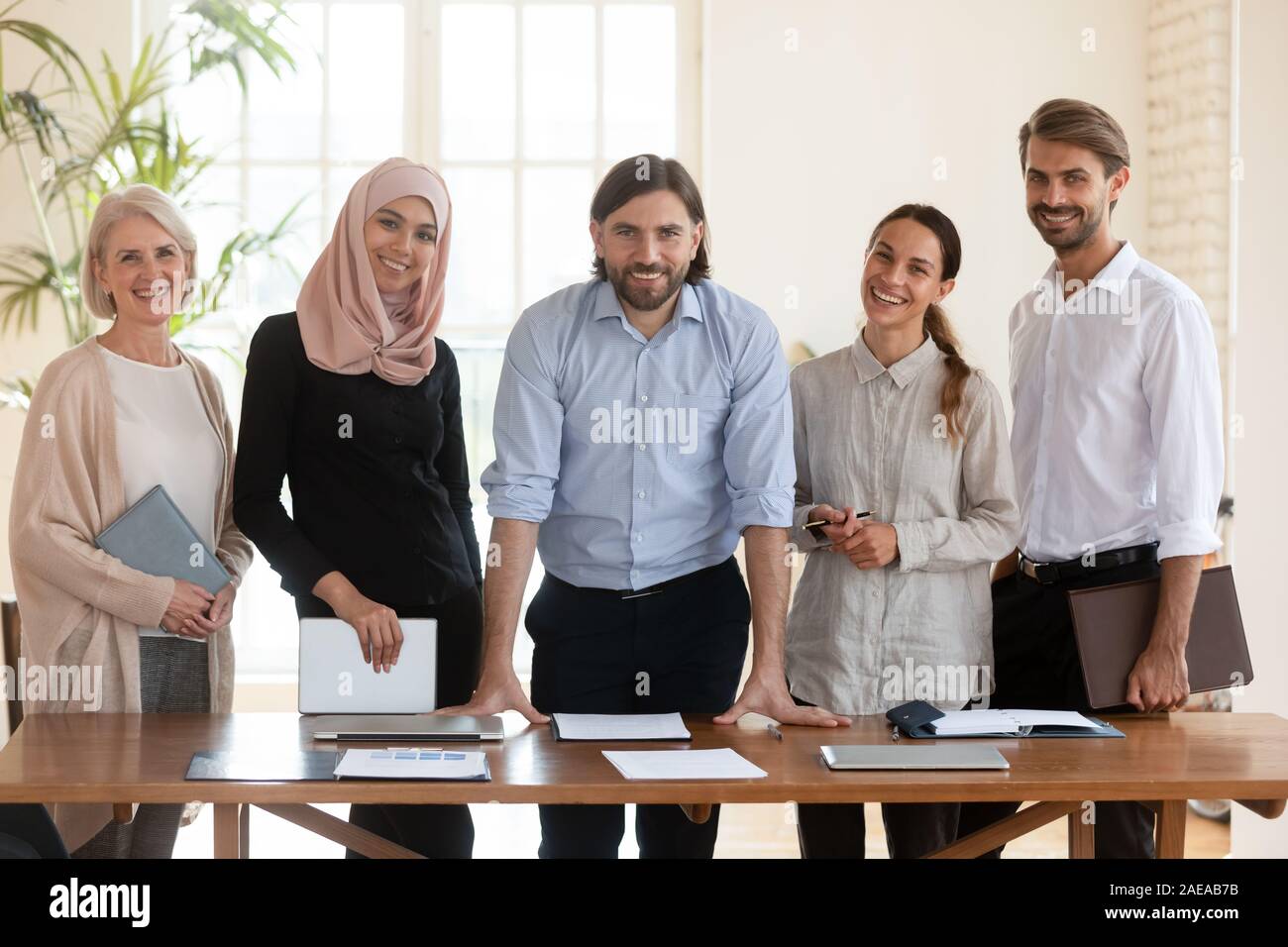 Portrait of confident male team leader with smiling diverse colleagues ...