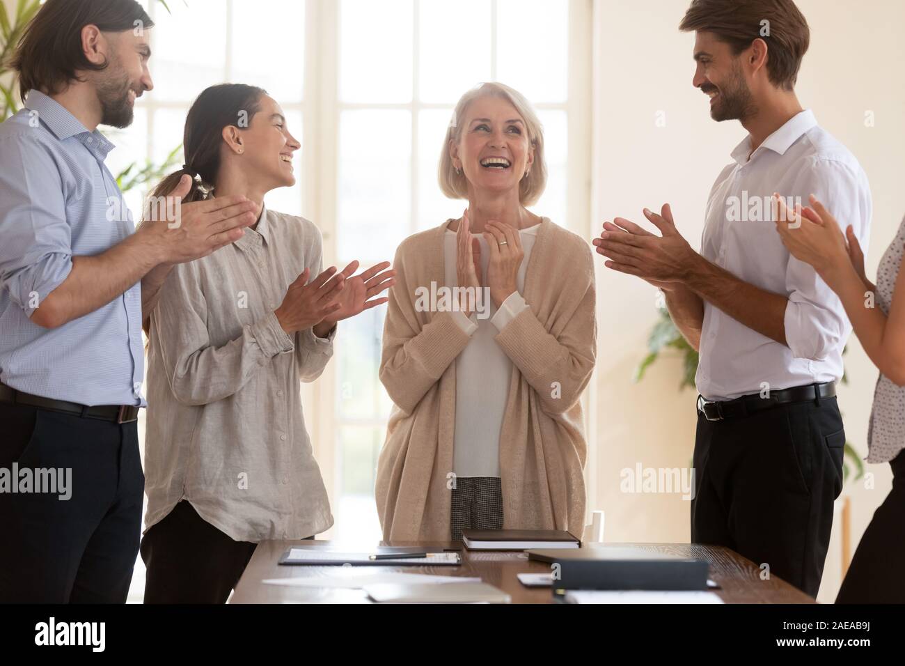 Happy middle aged team leader surprised by diverse colleagues ...