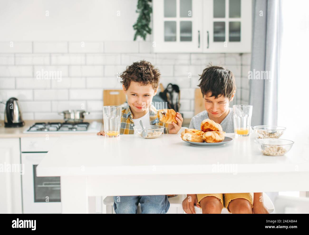 Two siblings tween boys real brothers with fun faces having breakfast ...