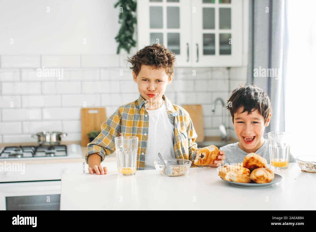 Two siblings tween boys real brothers with fun faces having breakfast ...