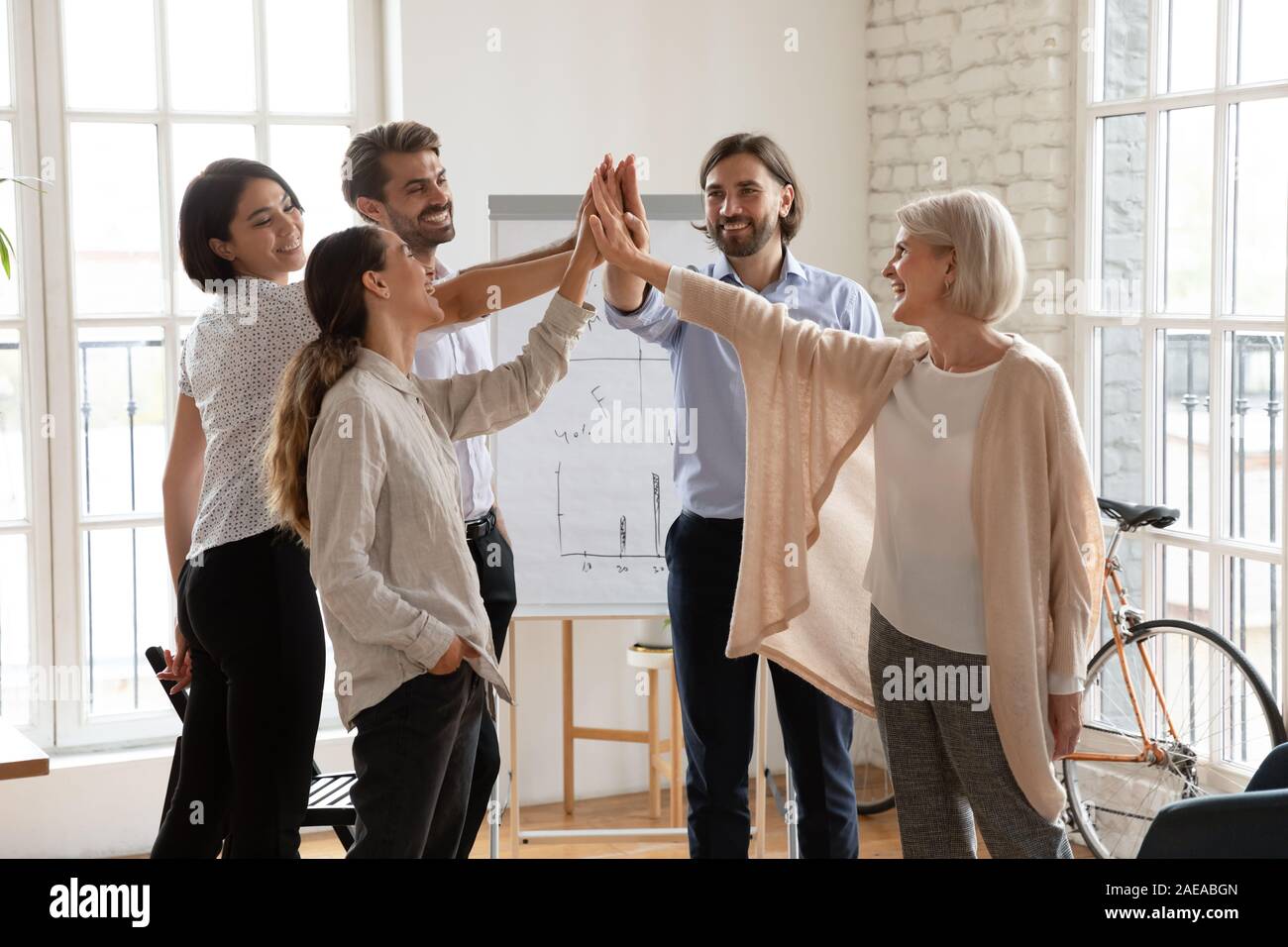 Happy international team giving high five to each other Stock Photo - Alamy