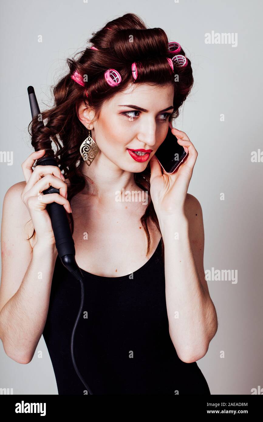 girl with hair curlers talking on the phone and makes the hairstyle ...