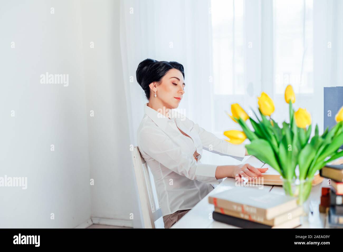 women in a business suit behind a table with books Stock Photo - Alamy