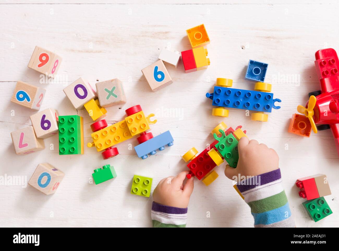 Child playing with wooden cubes with numbers and colorful toy bricks on ...