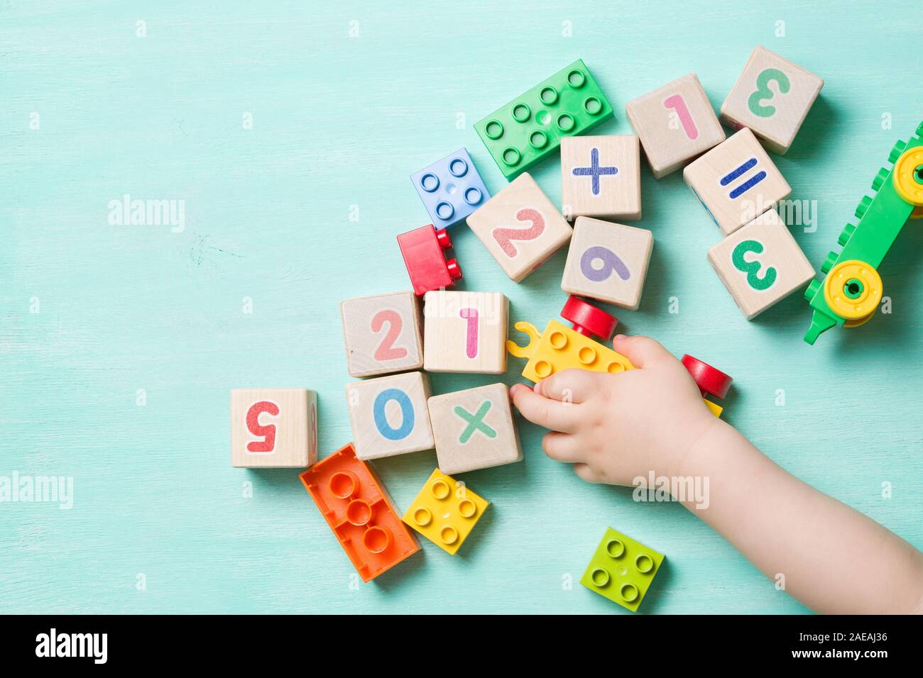 Child playing with wooden cubes with numbers and colorful toy bricks on ...