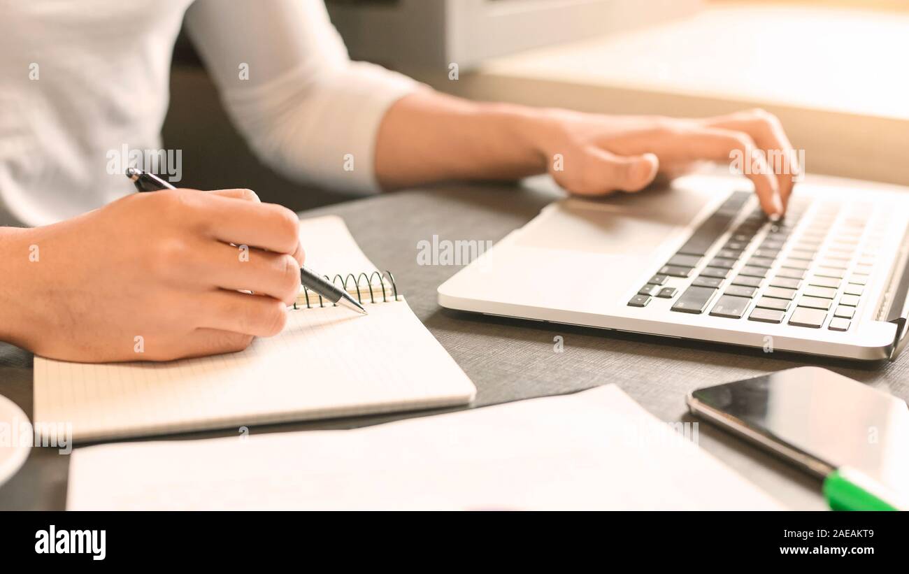 Skilled freelancer working on portable laptop and making notes Stock ...