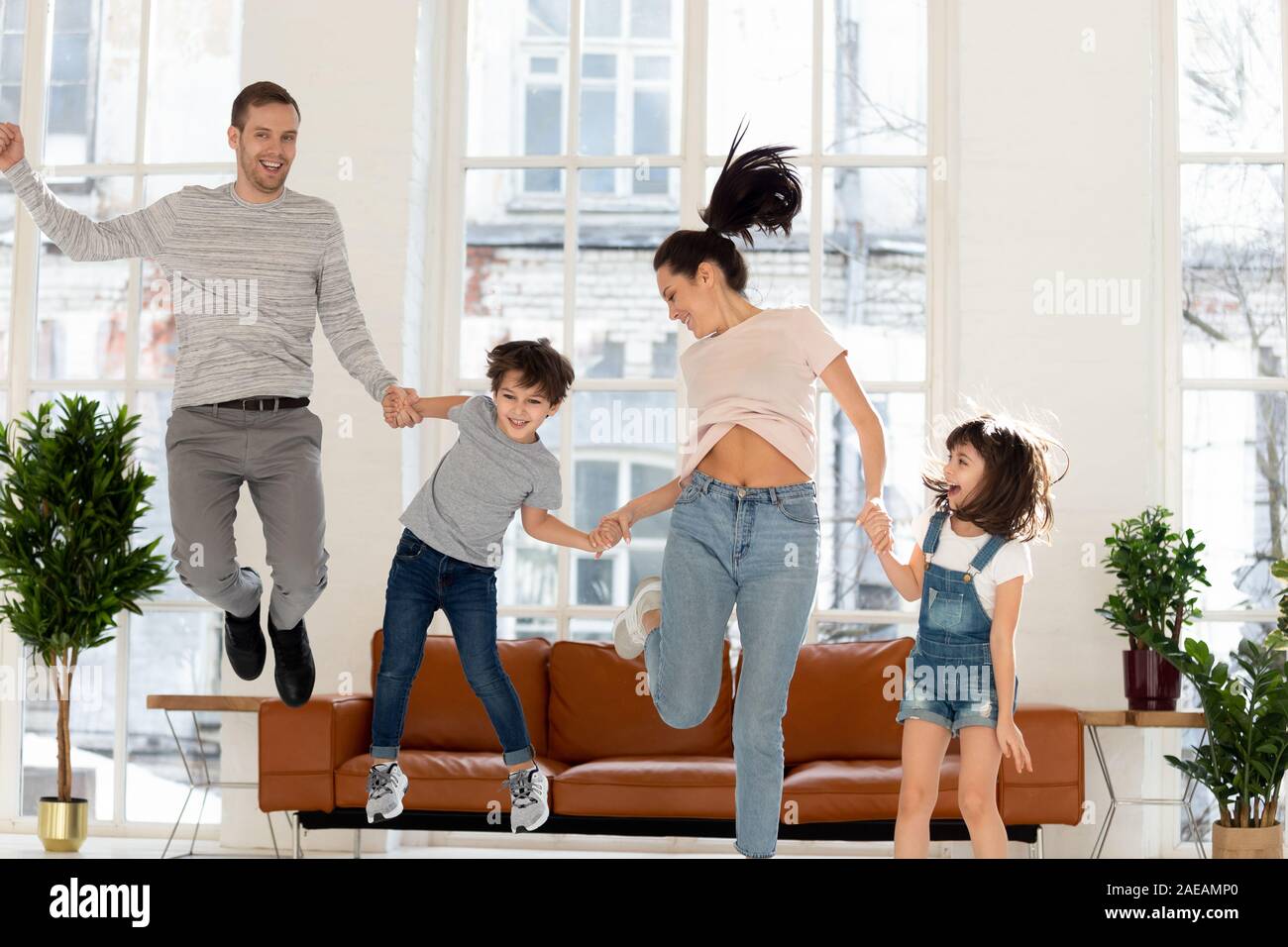 Happy family with two children jumping at home Stock Photo - Alamy