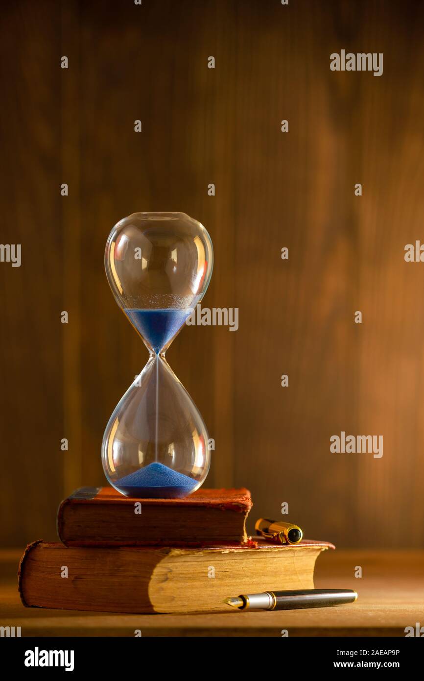 Hourglass on old book in morning light. Time of reading a book Stock ...