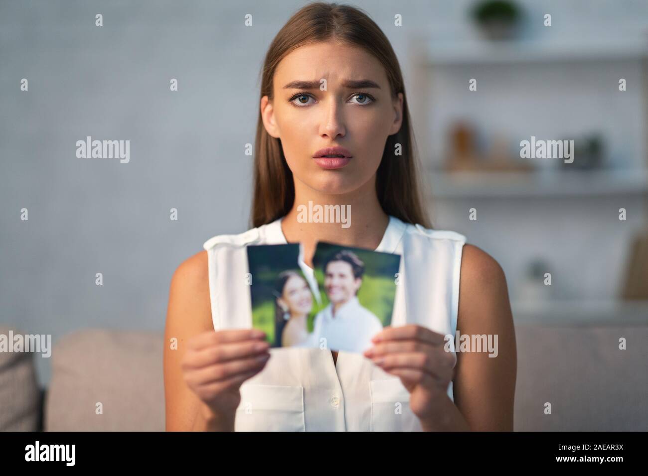 Woman Tearing Apart Wedding Photo With Ex-Husband Sitting On Sofa Stock ...