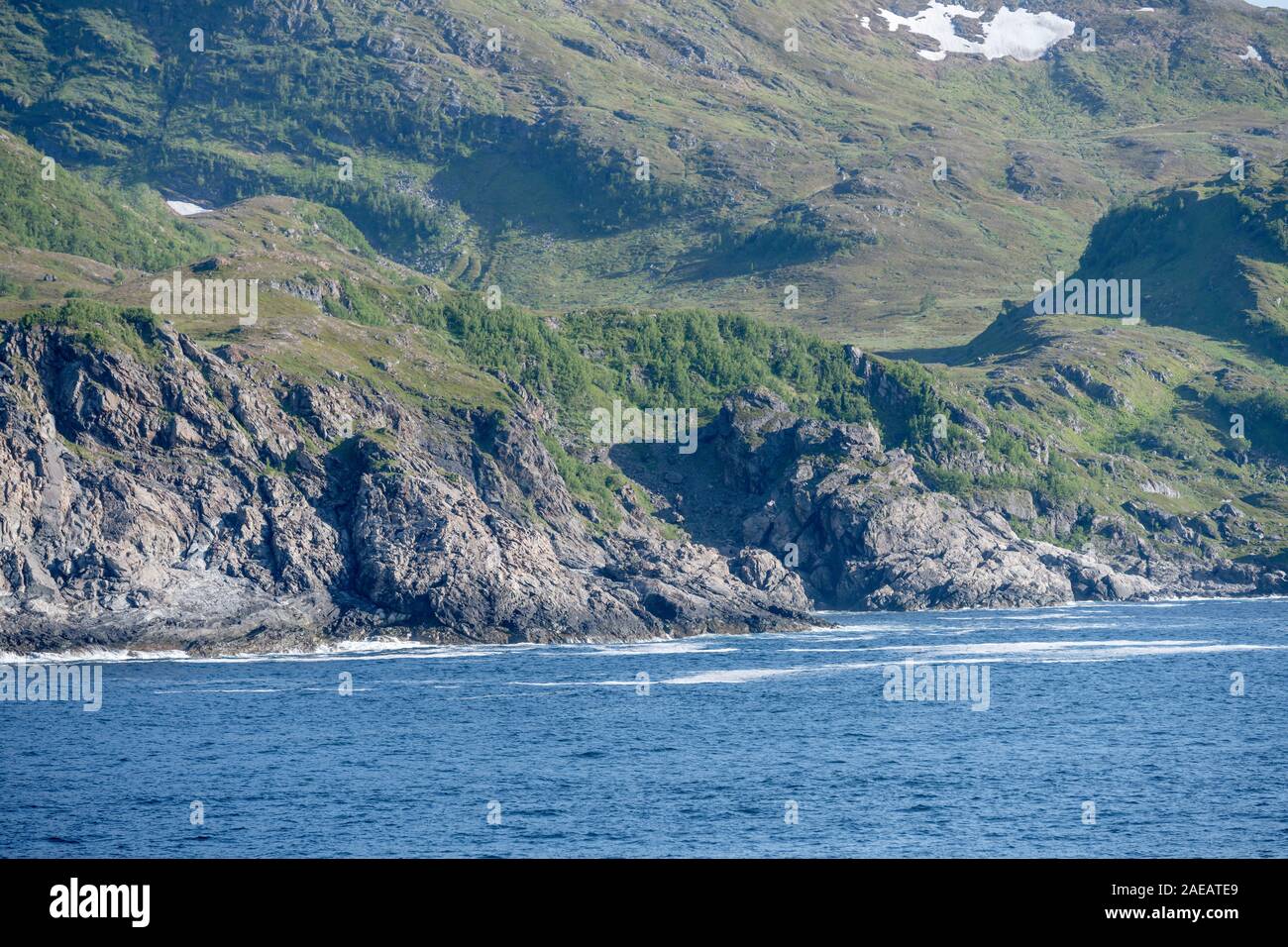 fjord landscape with steep rocks and some snow , shot under bright ...