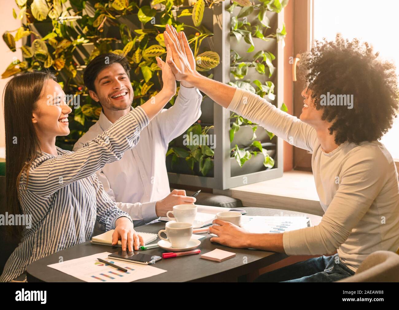 Partners giving one another high five during business lunch Stock Photo ...