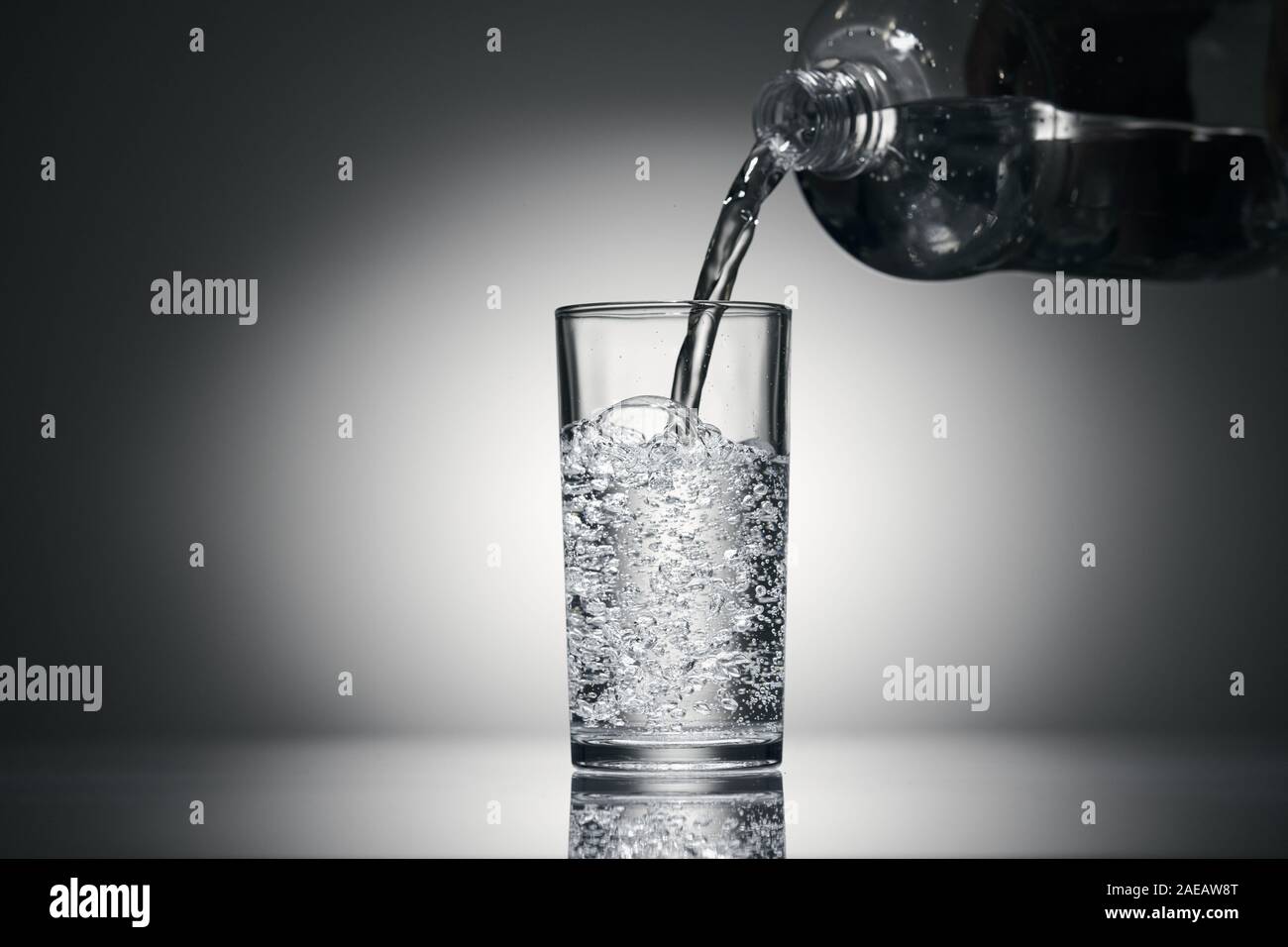 pouring sparkling water in a glass on a dark background Stock Photo - Alamy